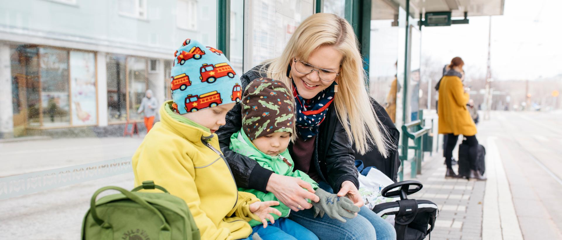 Äiti ja lapset raitiovaunupysäkillä